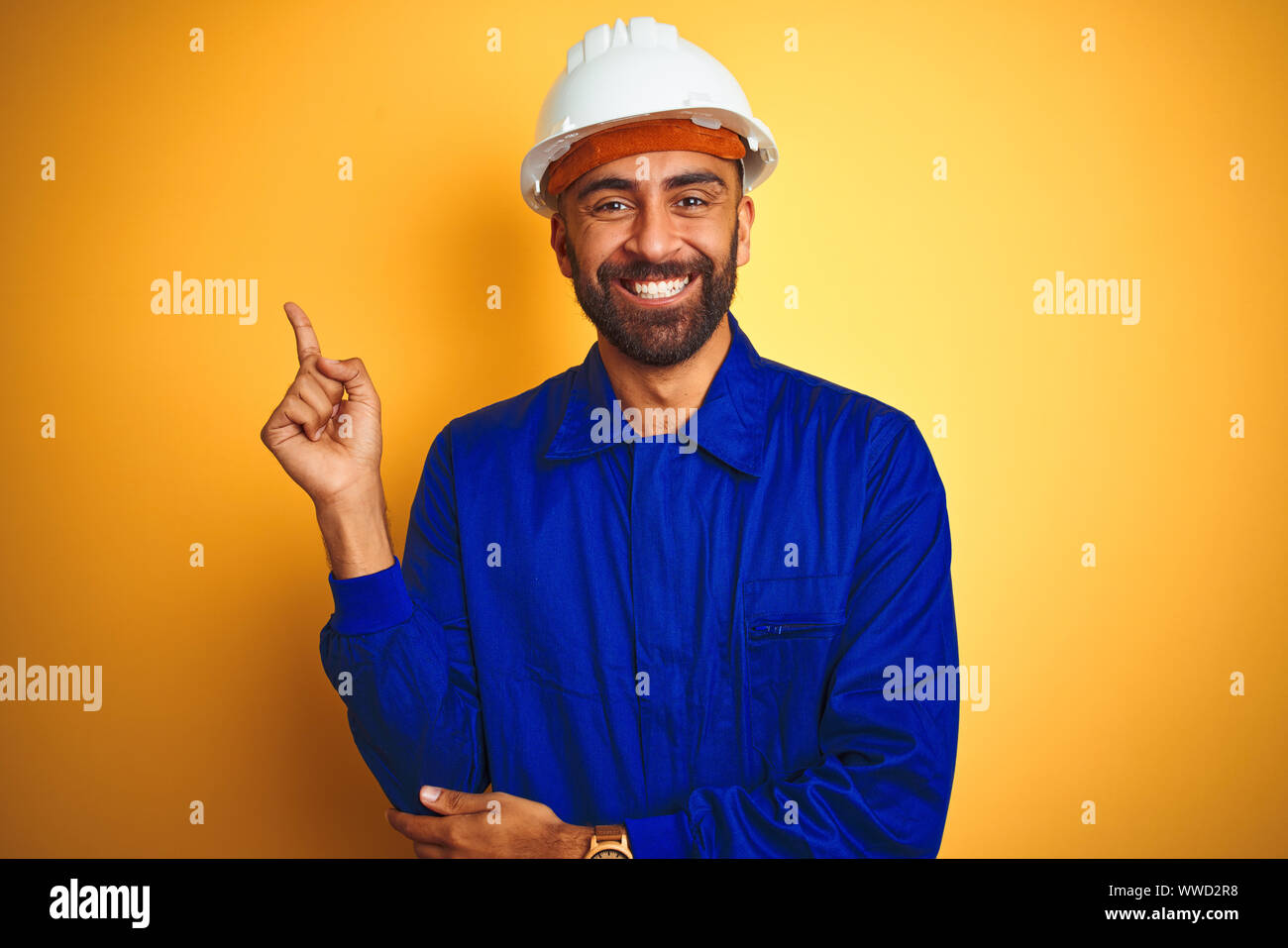 Handsome indian worker man wearing uniform and helmet over isolated ...