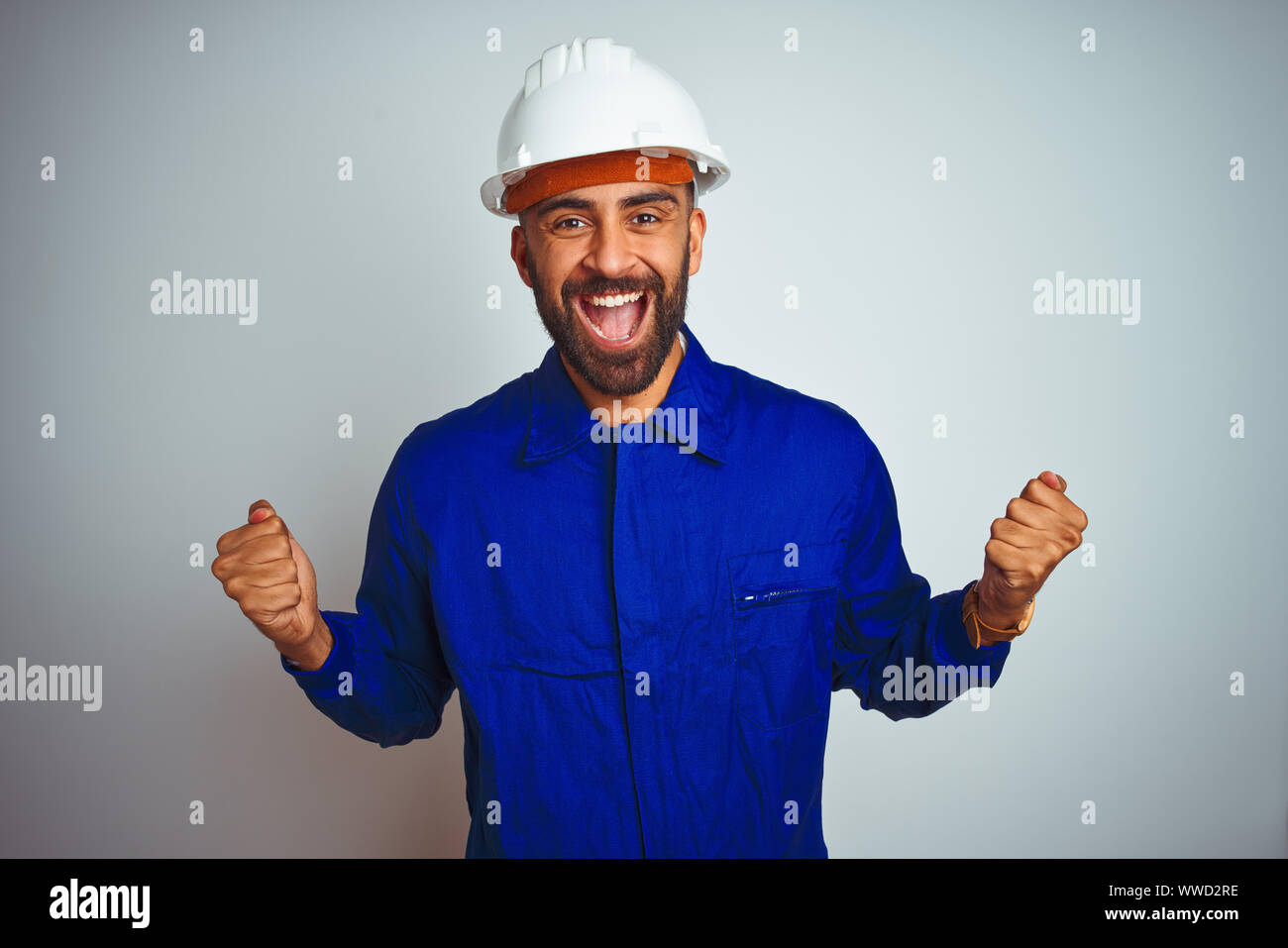 Handsome indian worker man wearing uniform and helmet over isolated ...