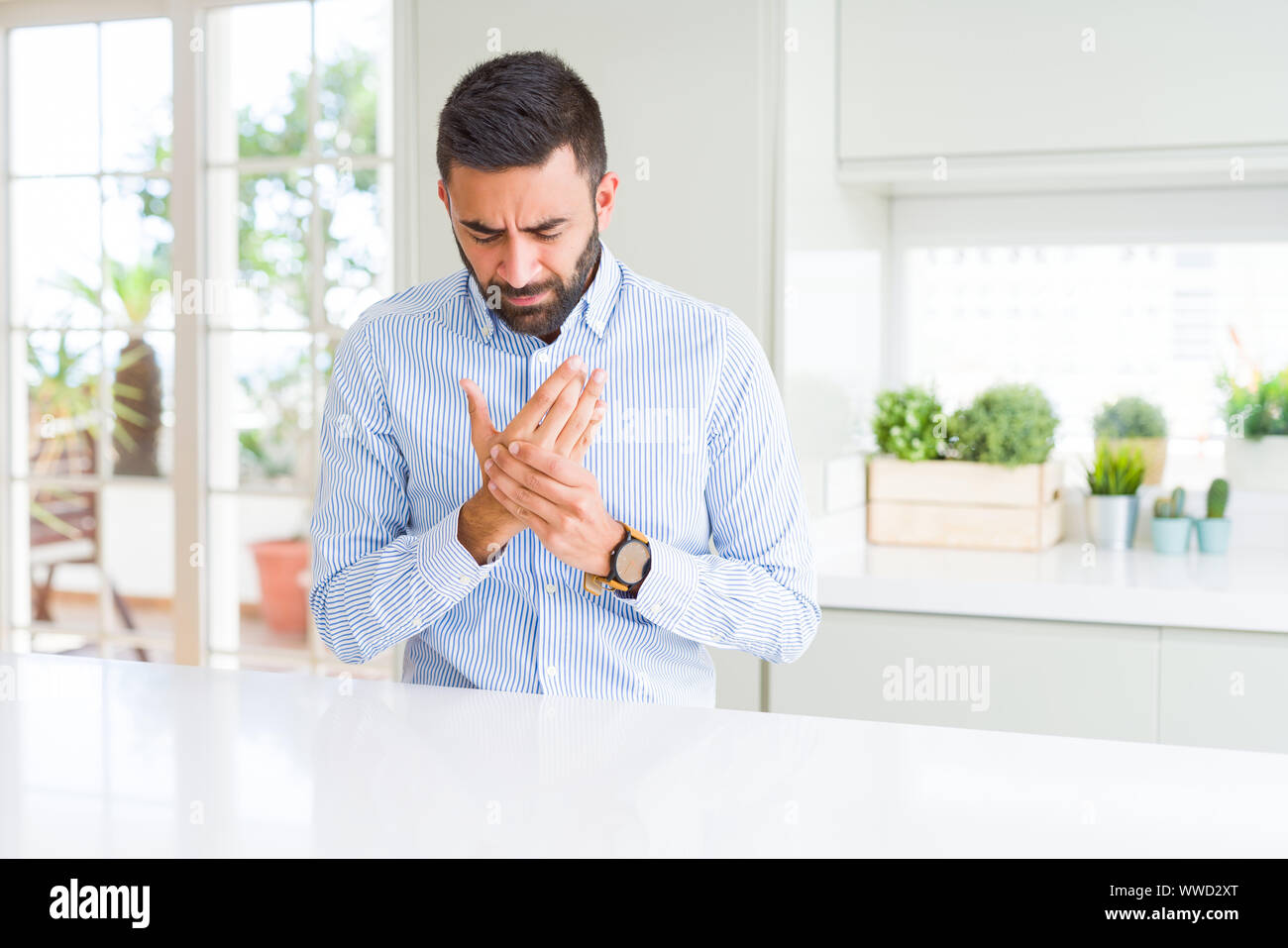 Handsome hispanic business man Suffering pain on hands and fingers ...