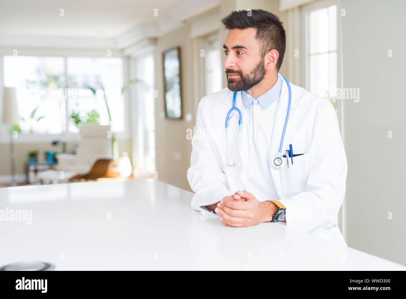 Handsome hispanic doctor man wearing stethoscope at the clinic looking ...