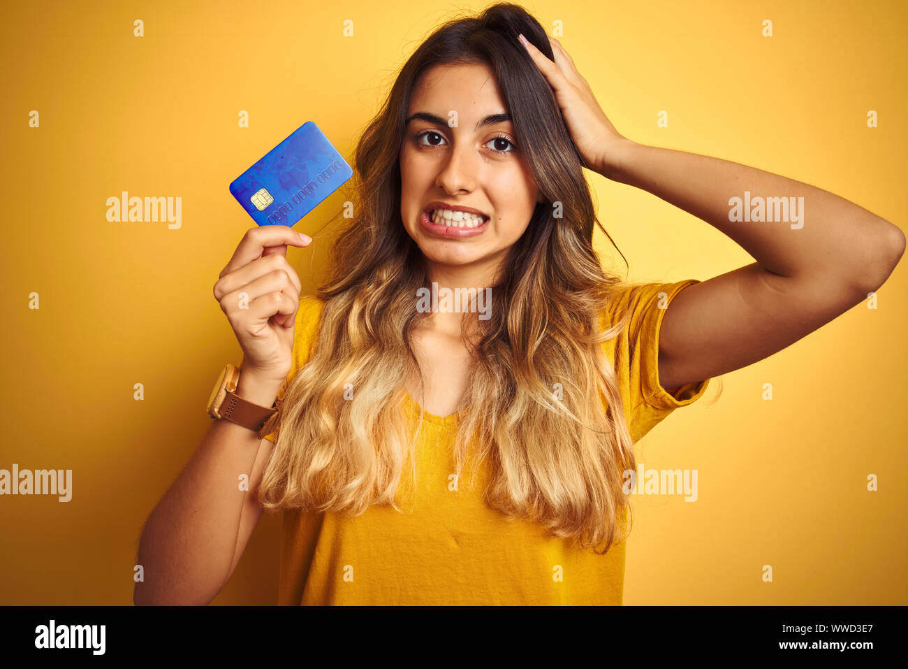 Young beautiful woman holding credit card over yellow isolated ...