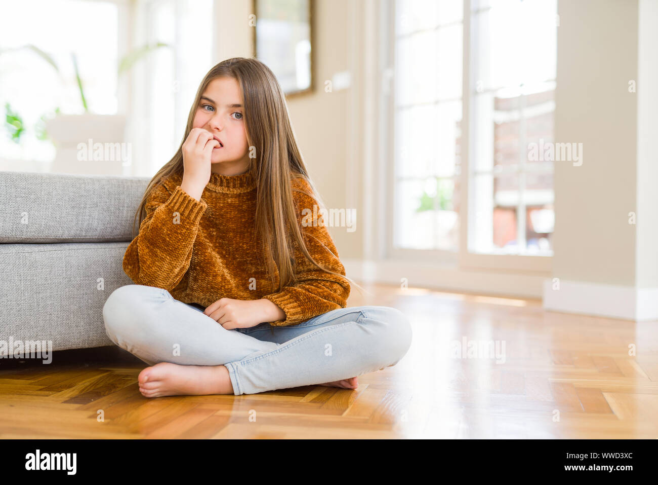 Beautiful young girl kid sitting on the floor at home looking stressed ...