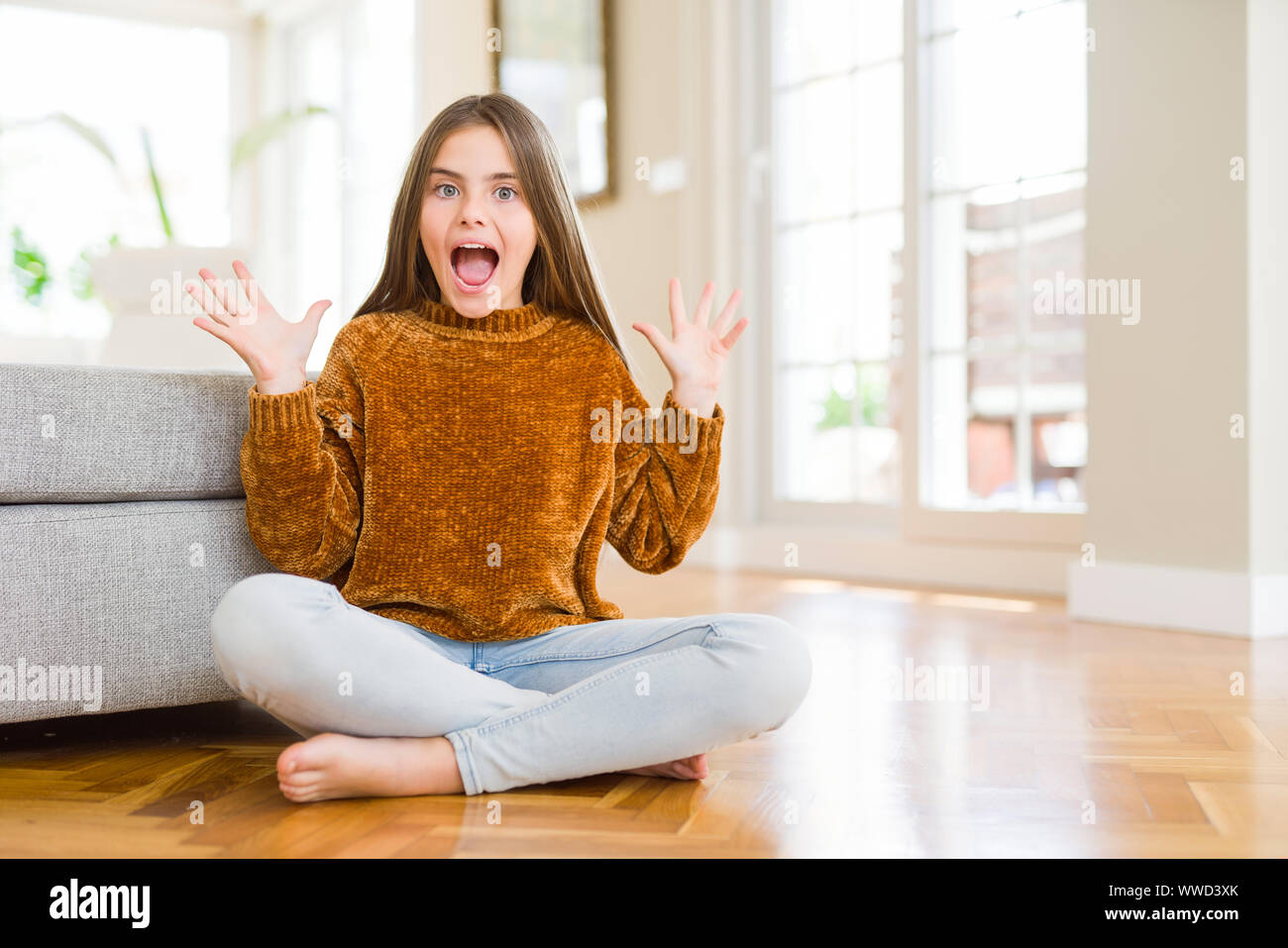 Beautiful young girl kid sitting on the floor at home celebrating crazy ...