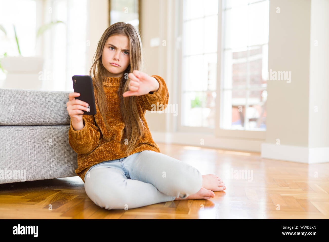 Beautiful young girl kid sending a message using smartphone with angry ...
