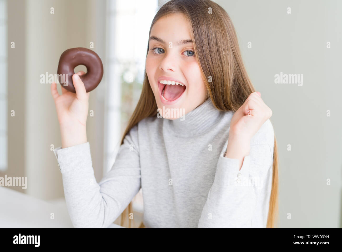 Beautiful young girl wearing eating a chocolate donut screaming proud ...