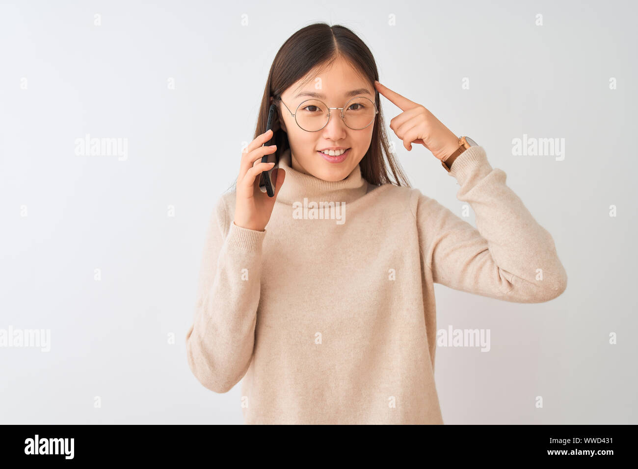 Young chinese woman talking on the smartphone over isolated white ...
