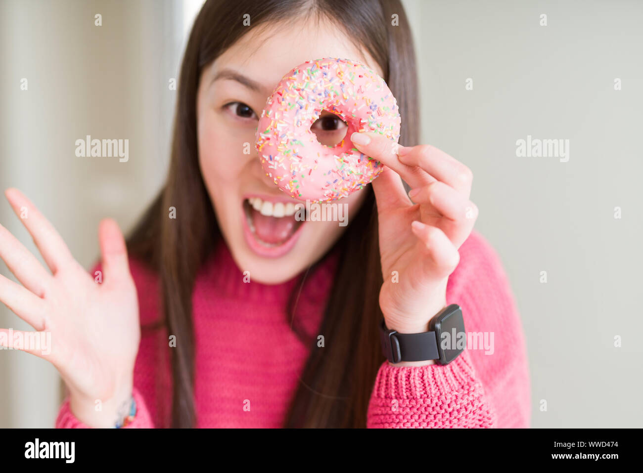 Beautiful Asian woman eating pink sugar donut very happy and excited ...