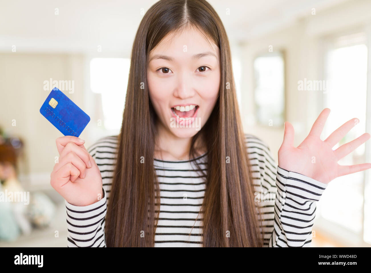Beautiful Asian woman holding credit card very happy and excited ...