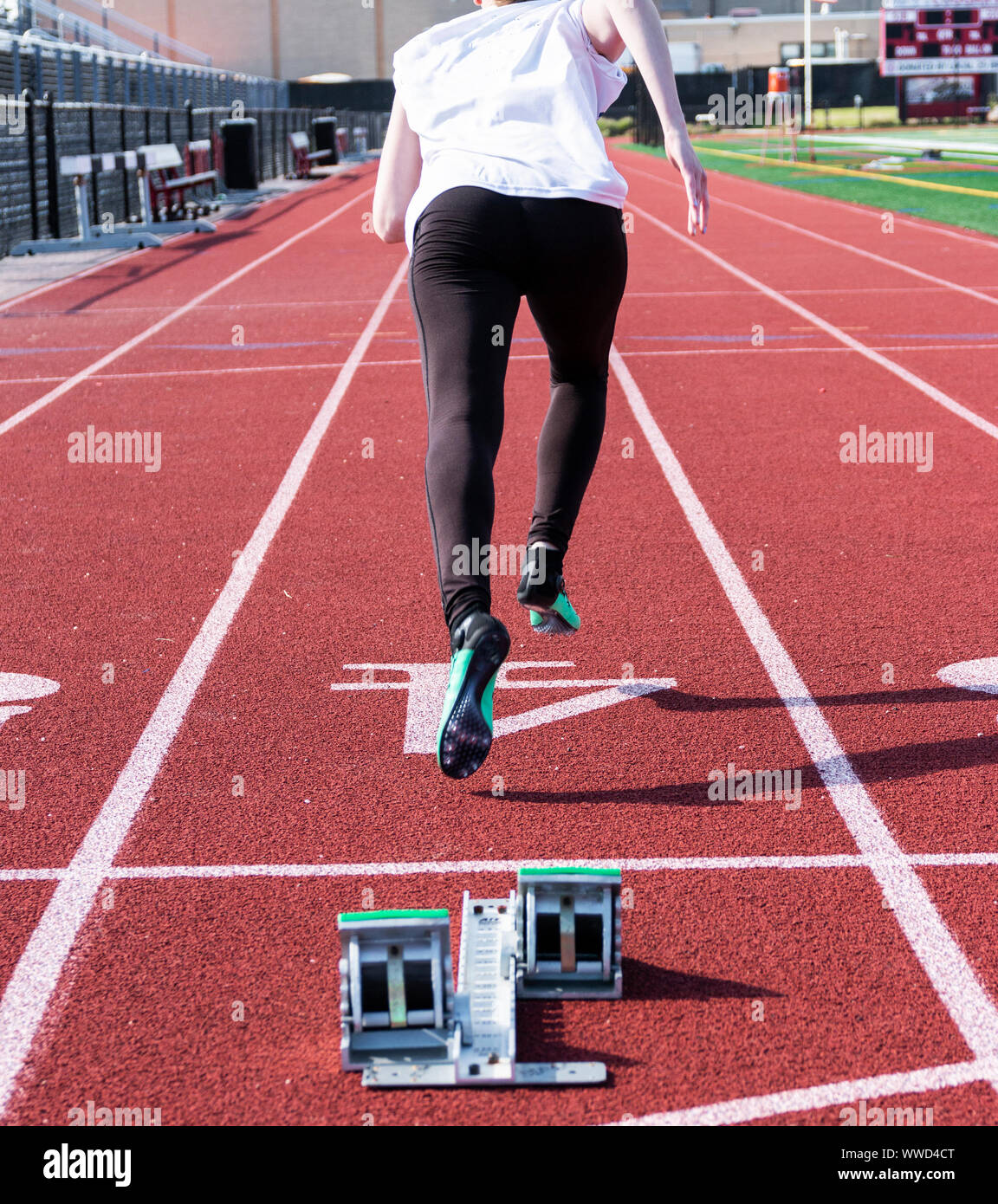 A high school girl is sprinting down the track after coming out of the ...
