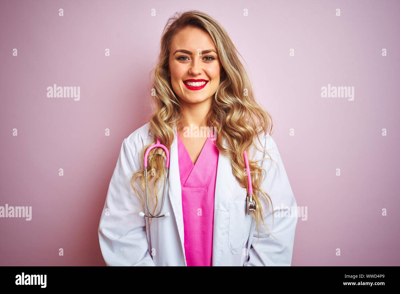 Young beautiful doctor woman using stethoscope over pink isolated ...