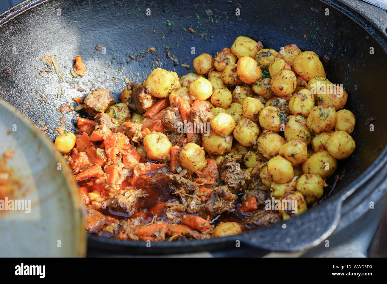 Roast meat and potatoes cooked in a large open-air boiler Stock Photo ...