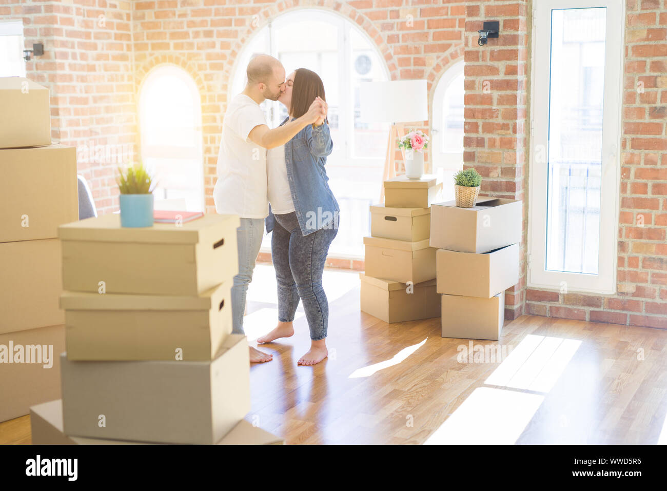 Young couple dancing around cardboard boxes at new home, celebrating ...