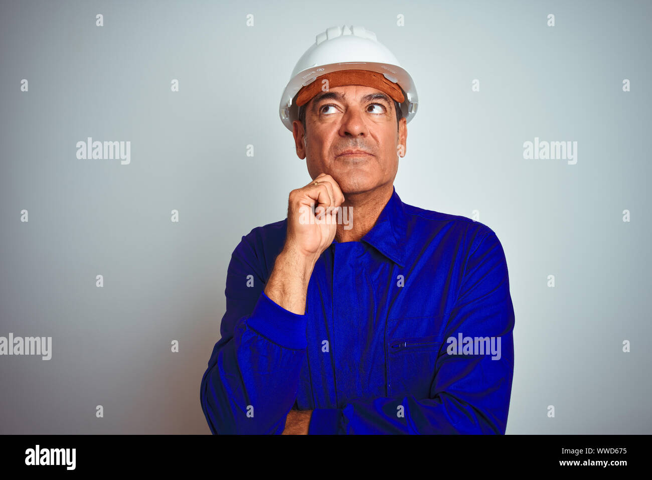 Handsome middle age worker man wearing uniform and helmet over isolated ...