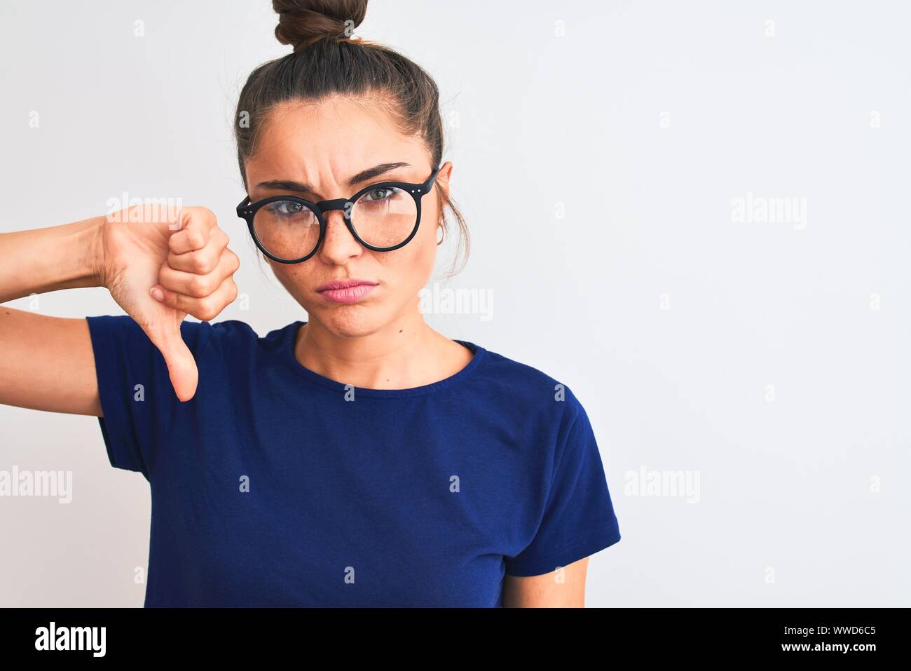 Beautiful woman with bun wearing blue t-shirt and glasses over isolated ...