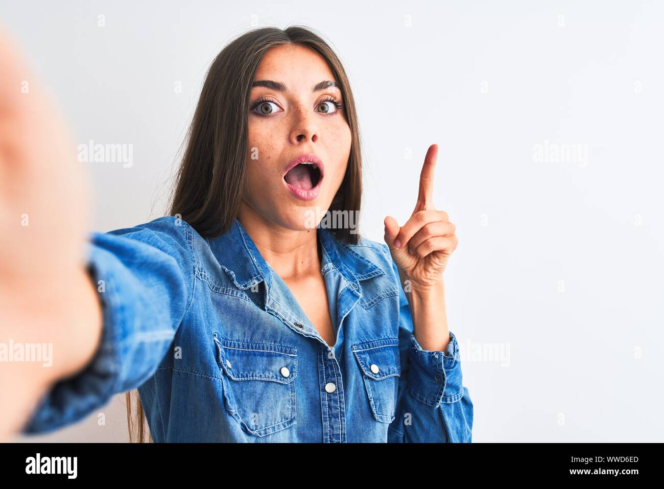 Beautiful woman wearing denim shirt make selfie by camera over isolated ...