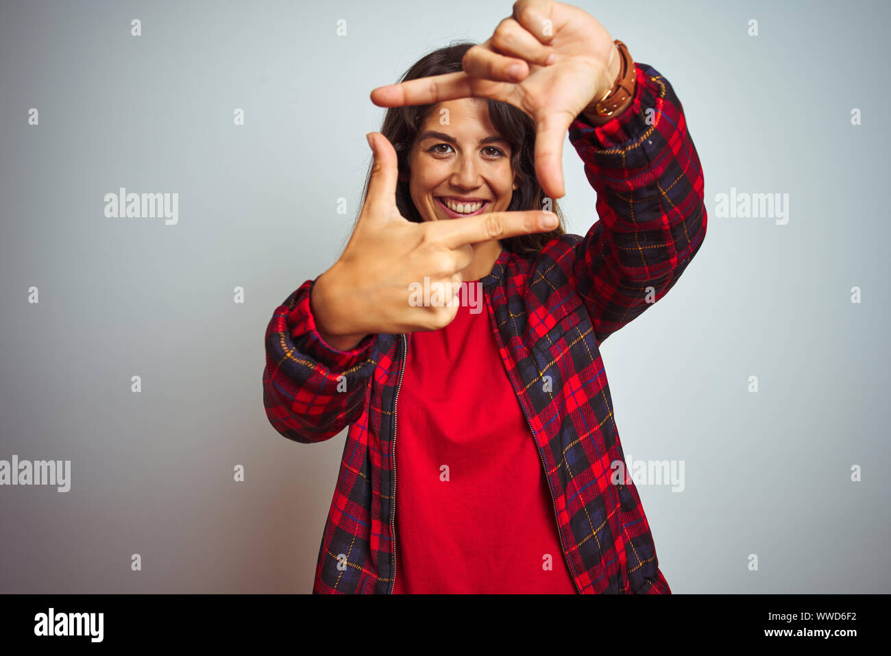 Young beautiful woman wearing red t-shirt and jacket standing over ...
