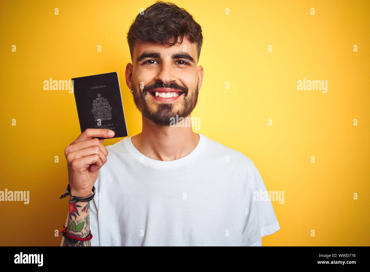 Young man with tattoo wearing Canada Canadian passport over isolated ...