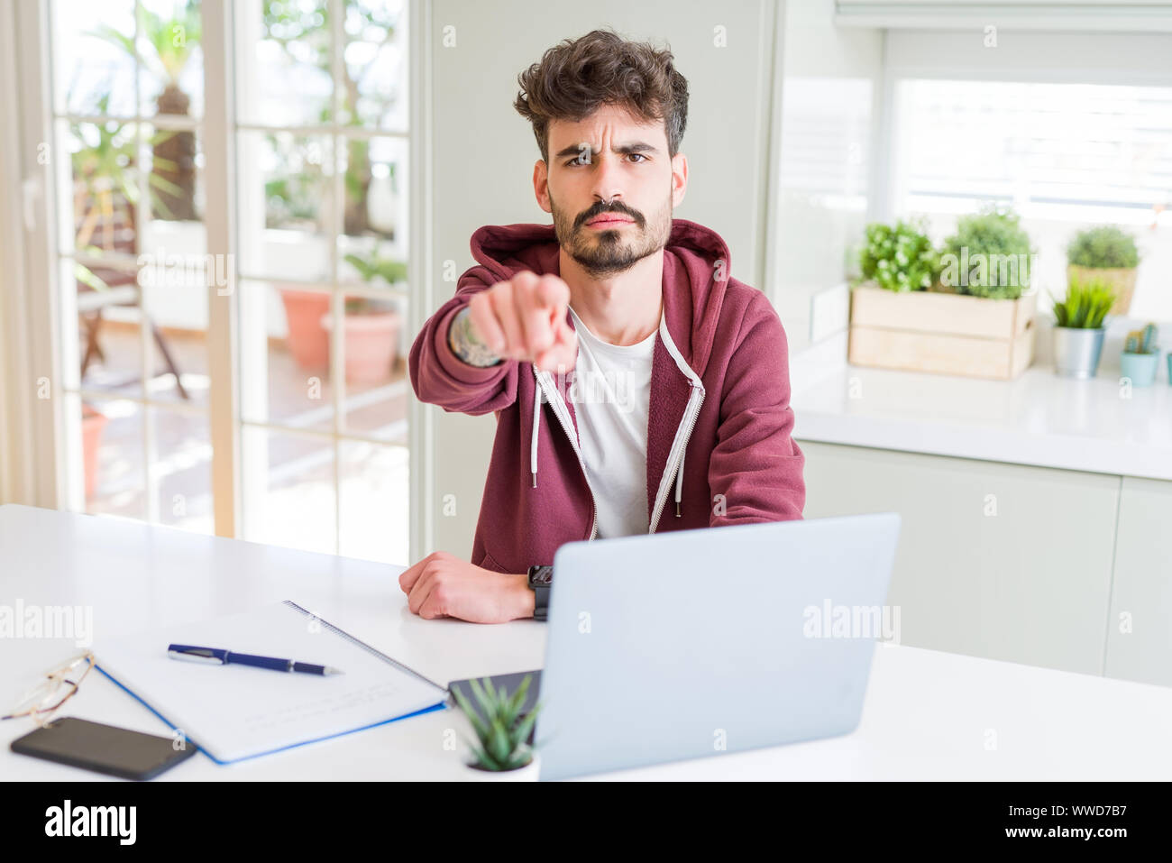 Young student man using computer laptop and notebook pointing with ...