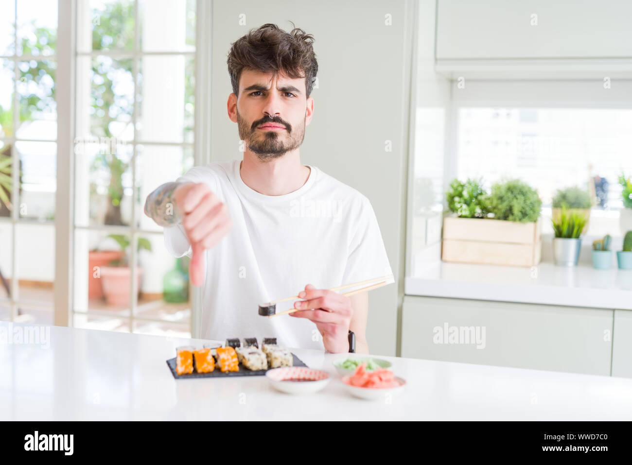 Young man eating asian sushi from home delivery with angry face ...
