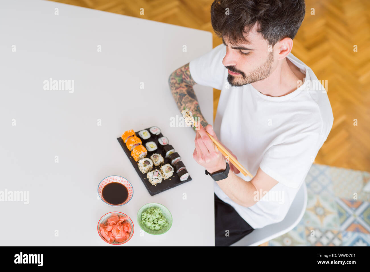 Overhead angle of young man eating sushi asian food using choopsticks ...