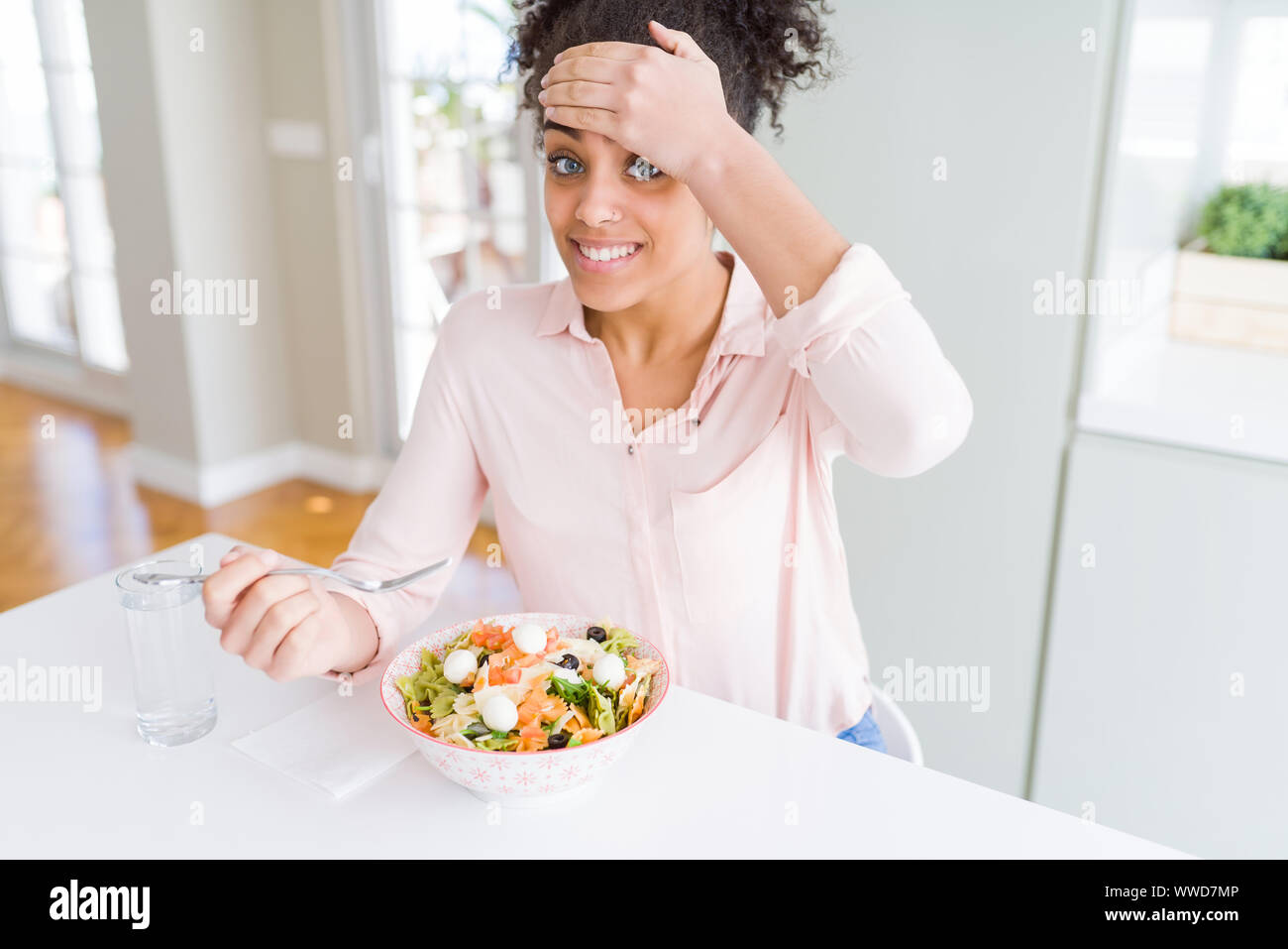 Young african american woman eating healthy pasta salad stressed with ...