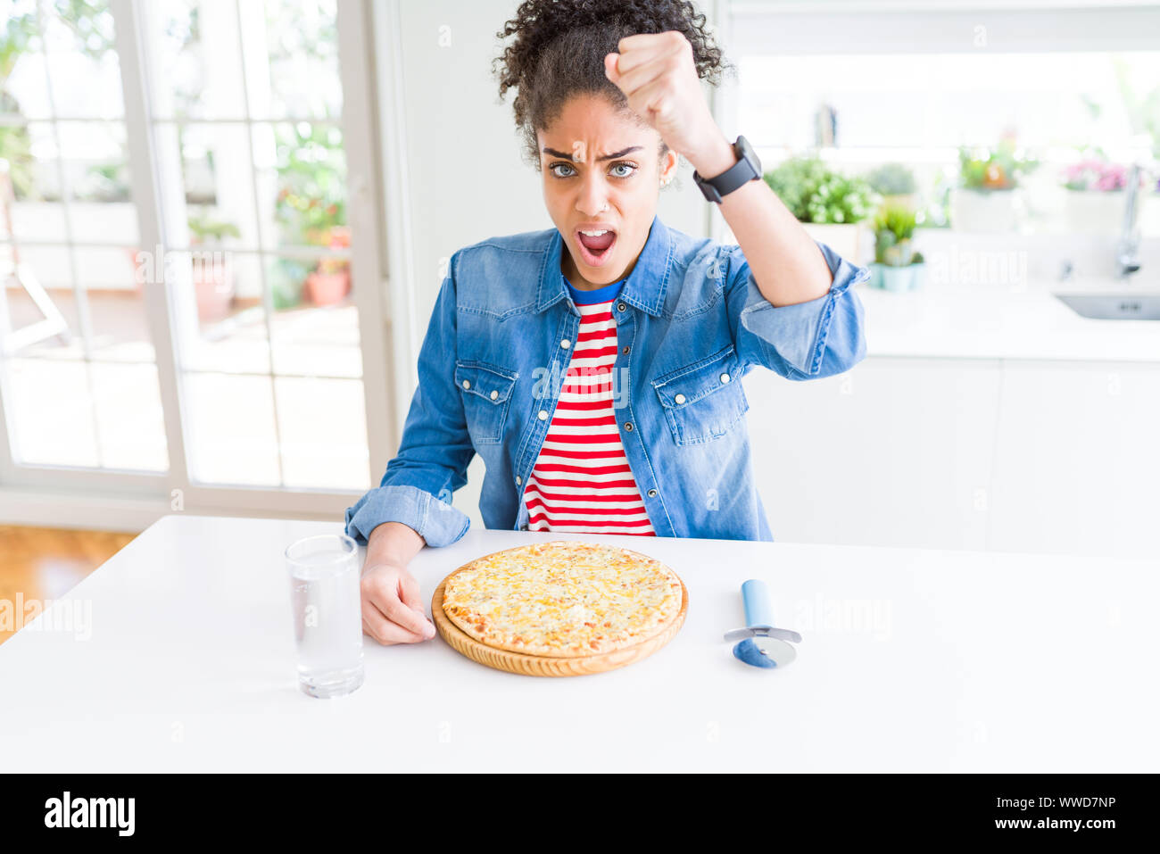 Young african american woman eating homemade cheese pizza annoyed and ...