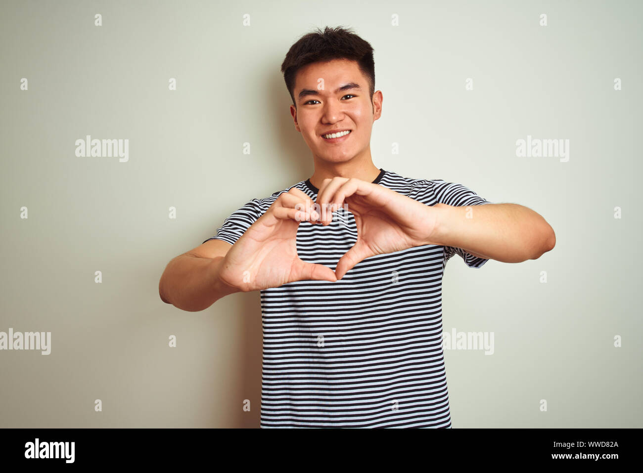Young asian chinese man wearing striped t-shirt standing over isolated ...