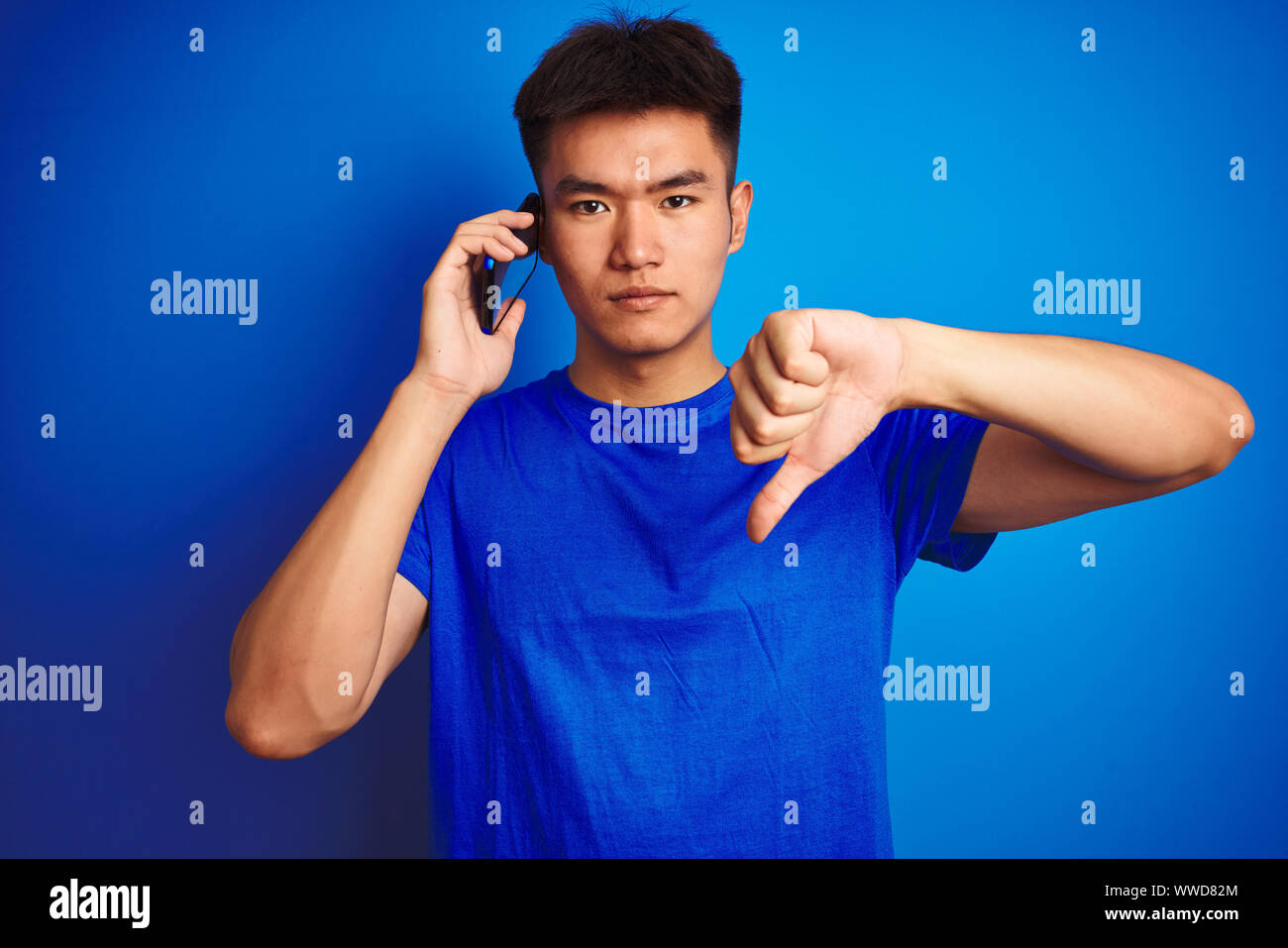Young asian chinese man talking on the smartphone standing over ...
