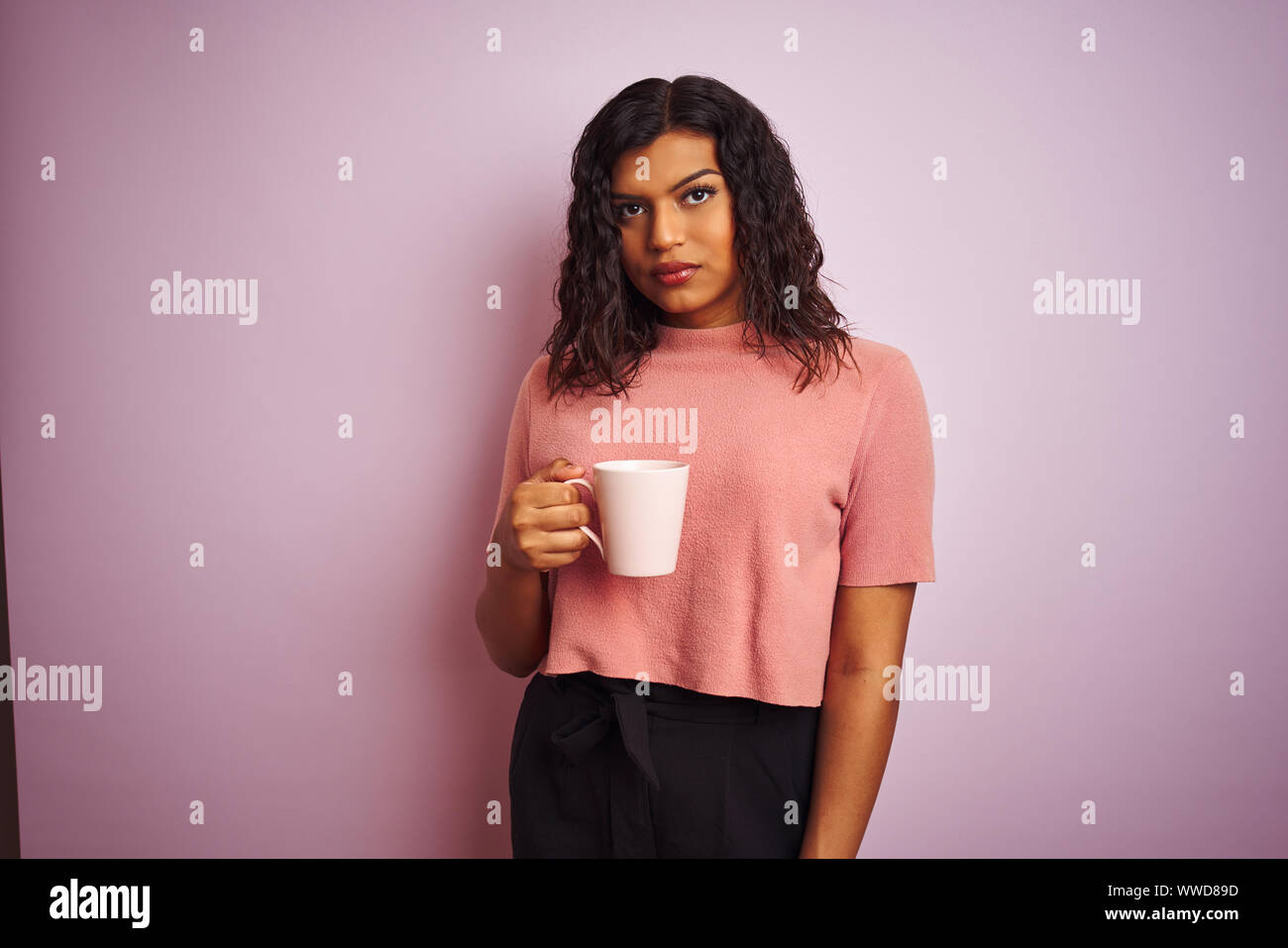 Transsexual transgender woman drinking cup of coffee over isolated pink ...