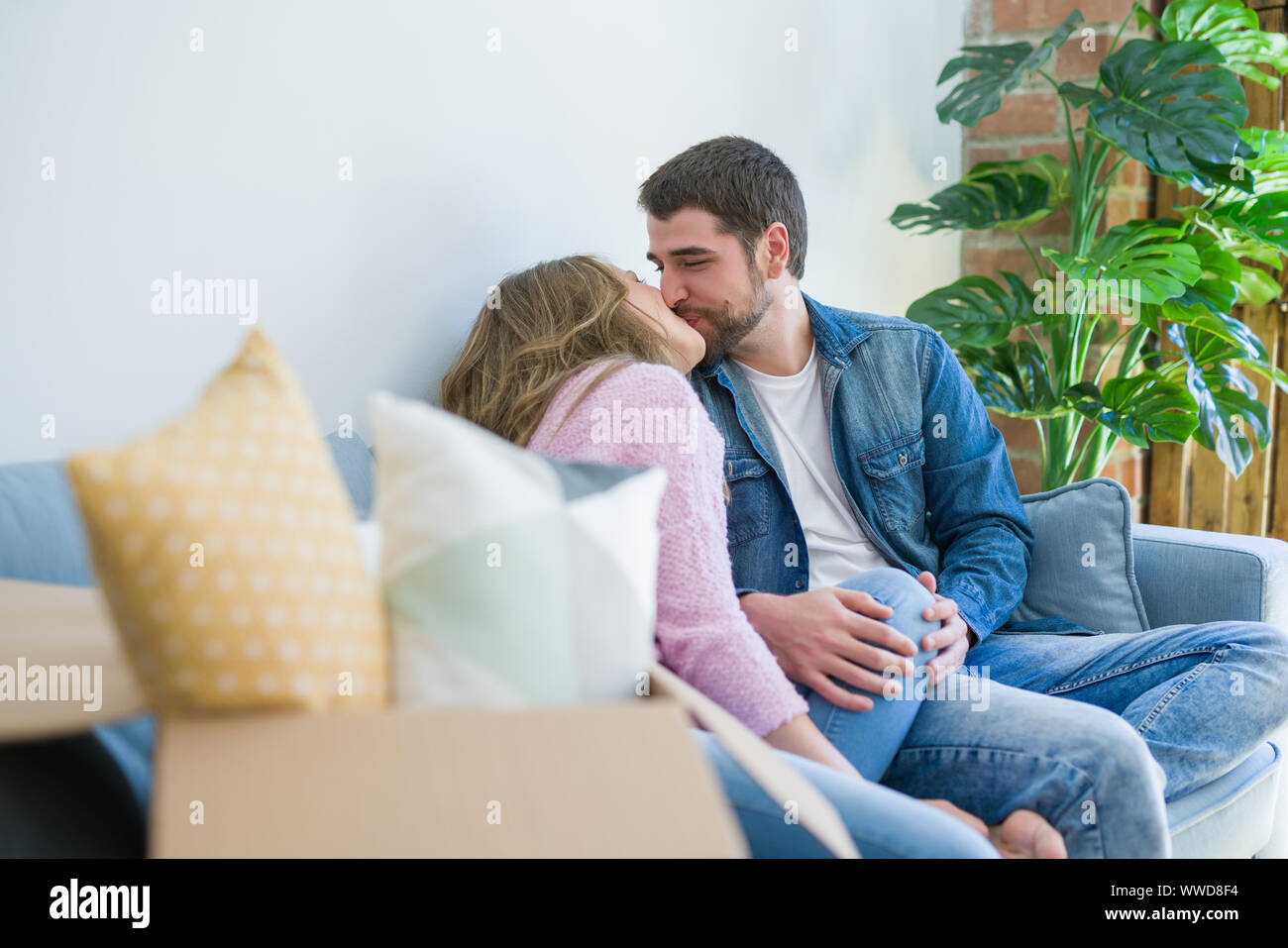 Young couple in love hugging sitting on the sofa very happy moving to a ...
