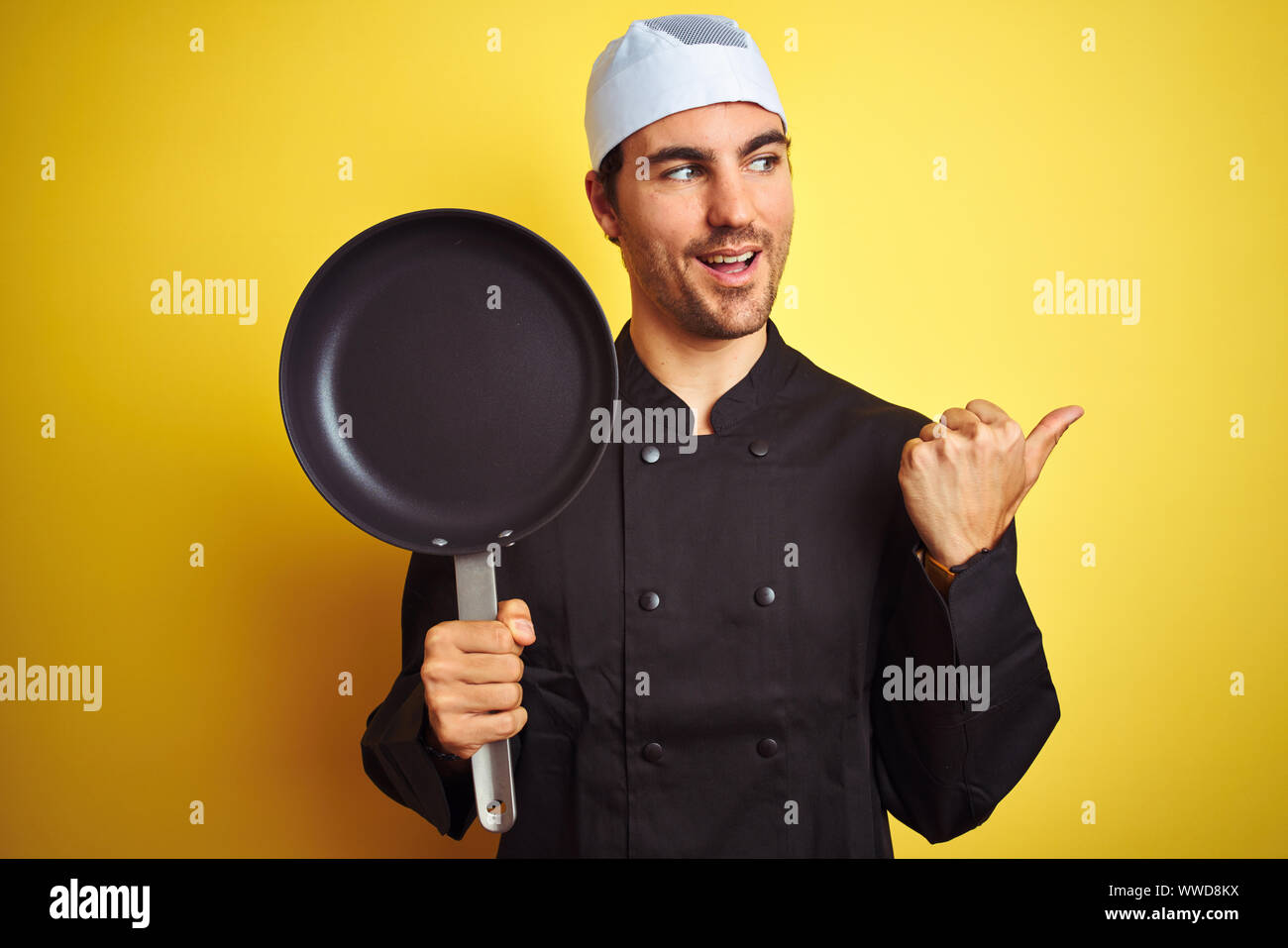 Young chef man wearing uniform and hat holding cook pan over isolated ...