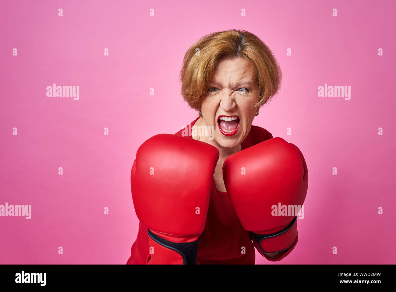 Woman aged in boxing gloves. The concept of the fight against old age ...