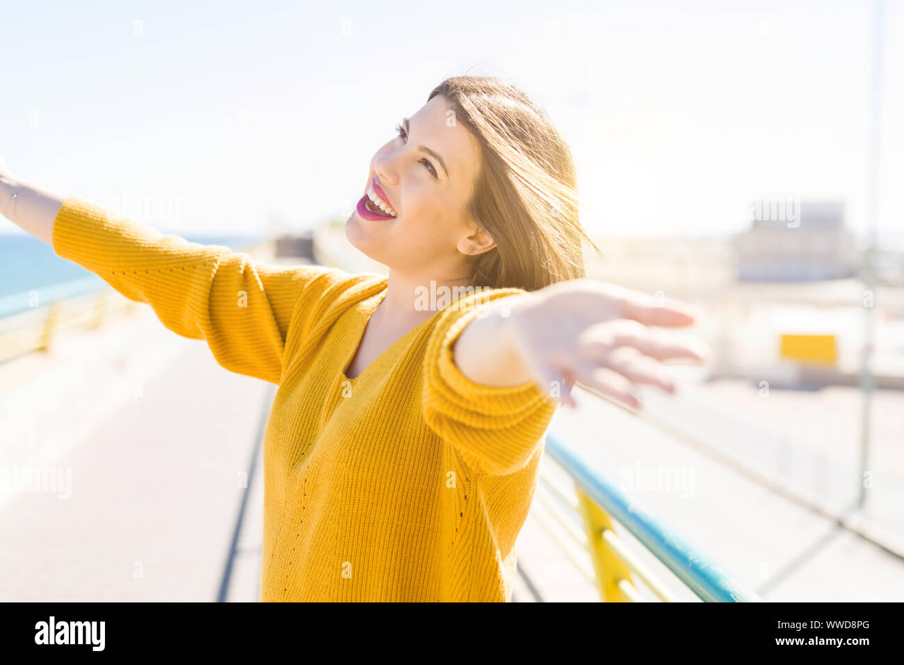 Beautiful young woman smiling with closed eyes and open arms enjoying ...