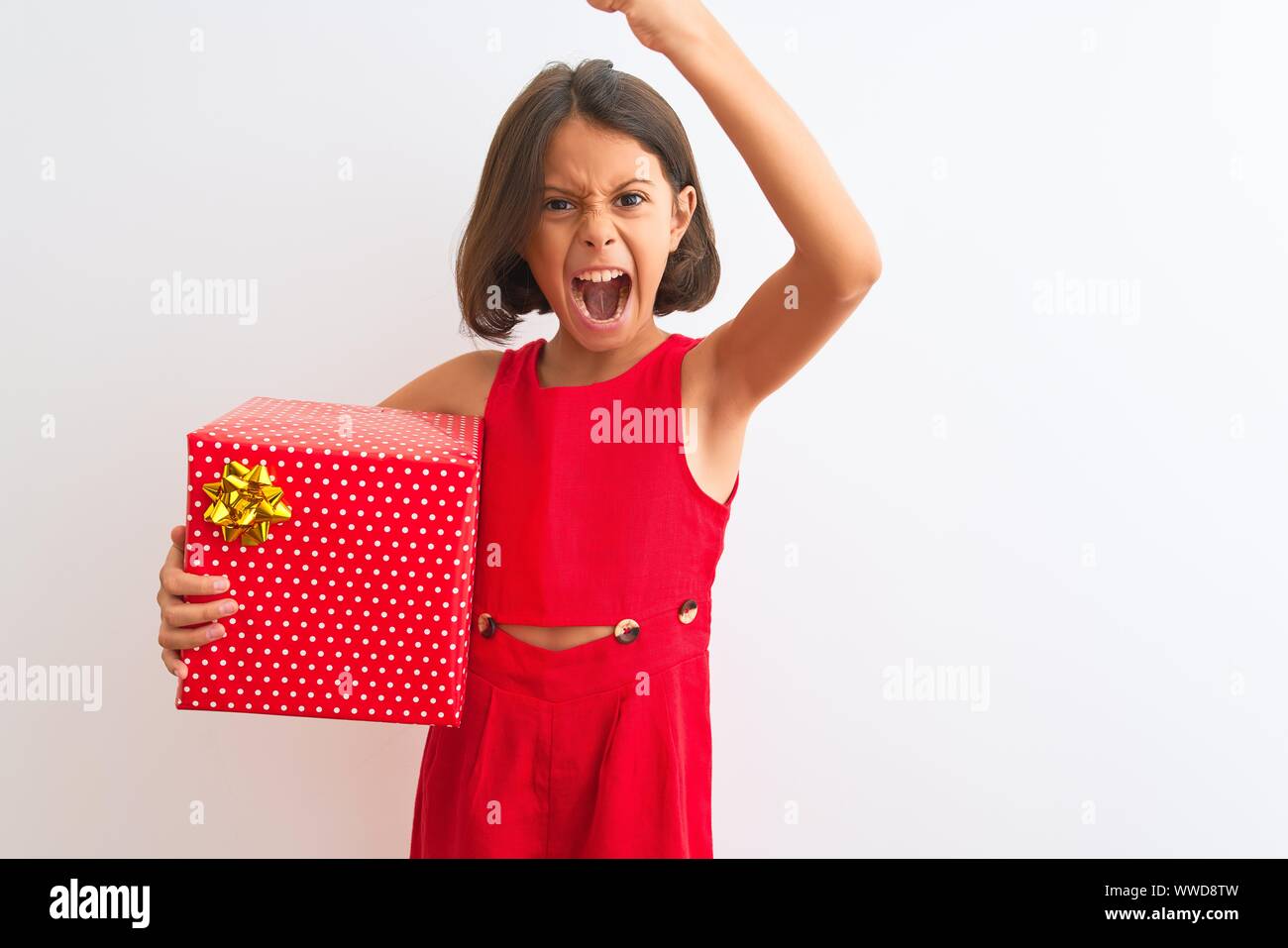 Beautiful child girl holding birthday gift standing over isolated white ...