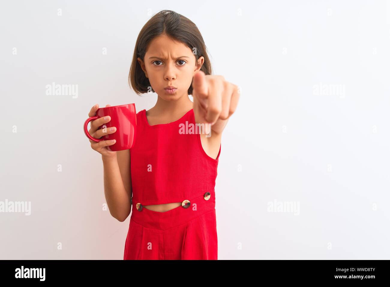 Beautiful child girl holding red cup of tea standing over isolated ...
