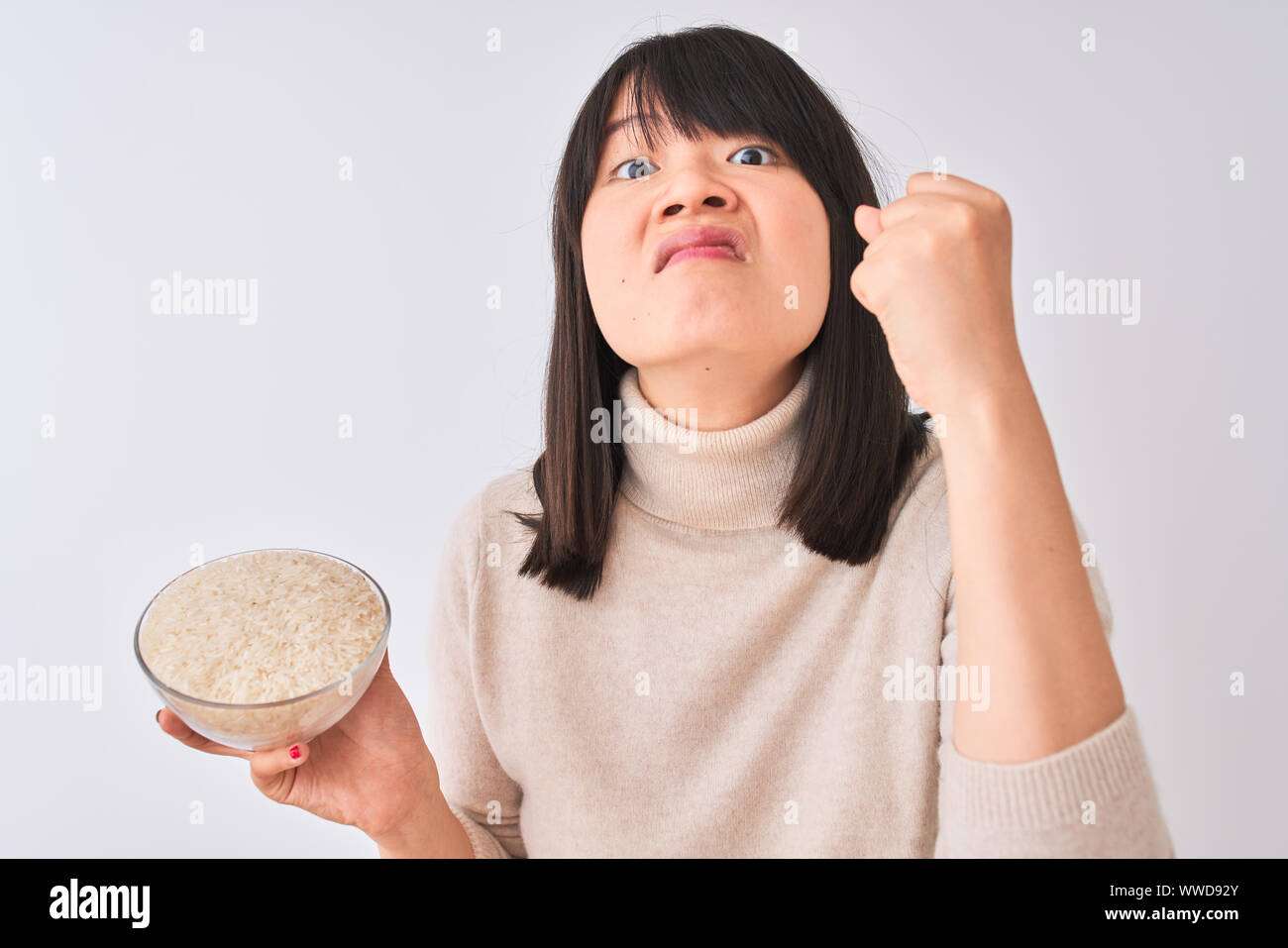 Young beautiful Chinese woman holding bowl with rice over isolated ...