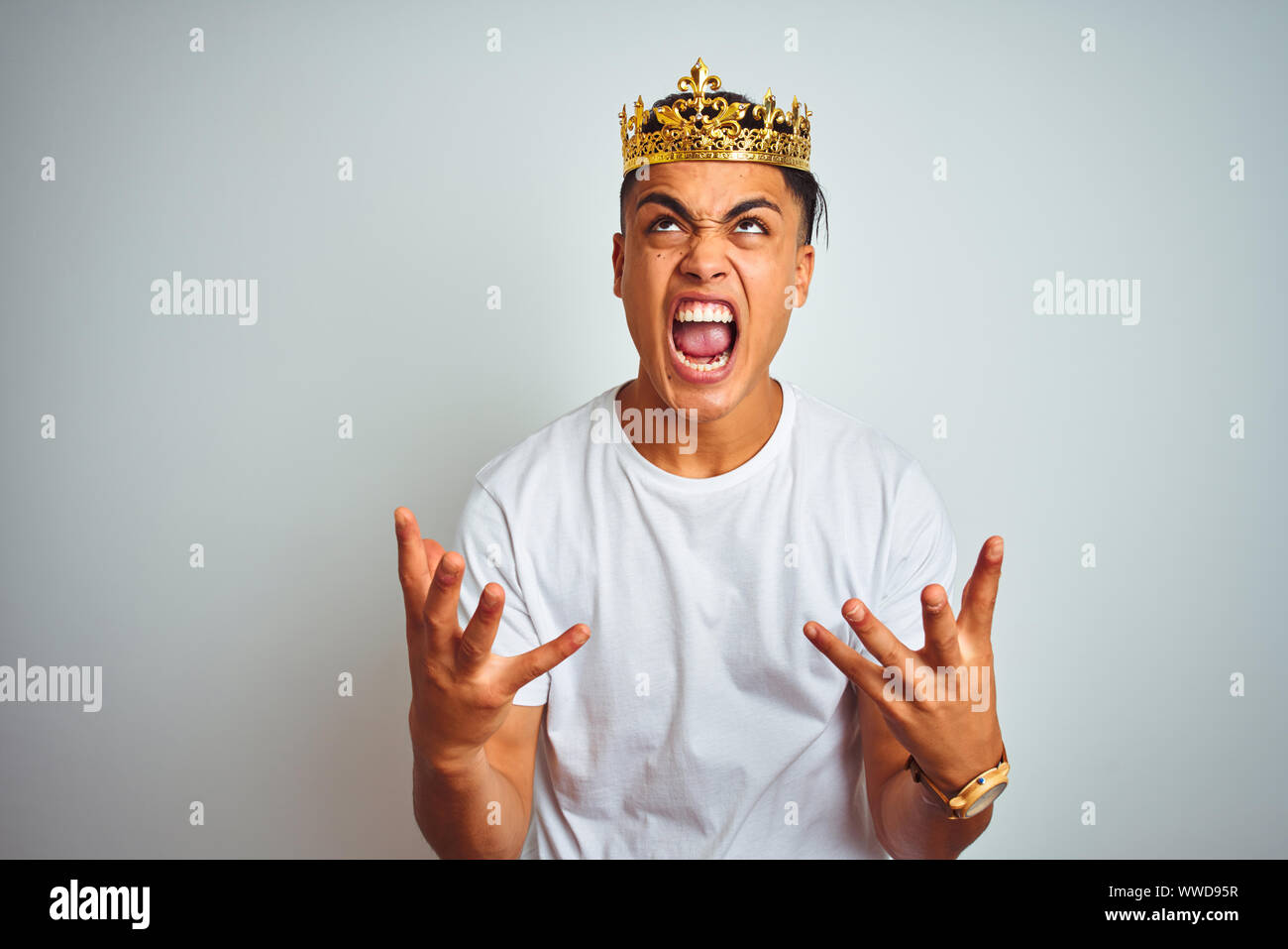 Young brazilian man wearing king crown standing over isolated white ...