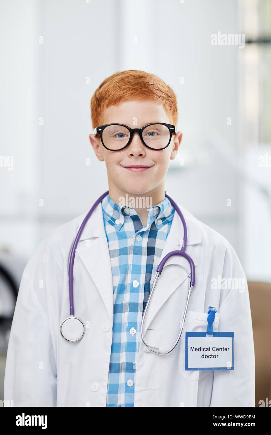 Waist up portrait of cute red haired boy posing as doctor wearing white ...
