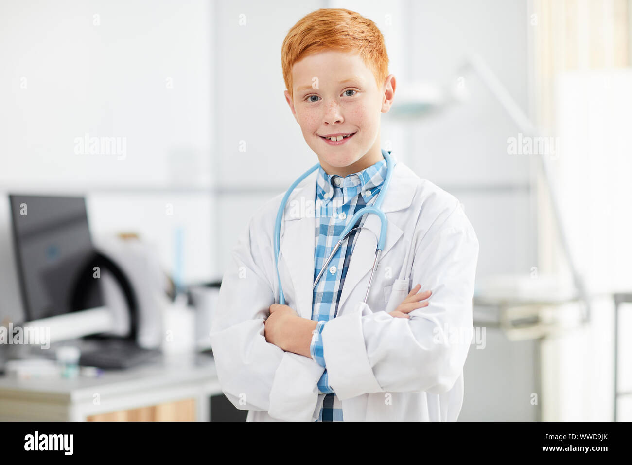 Waist up portrait of cute red haired boy posing as doctor wearing white ...