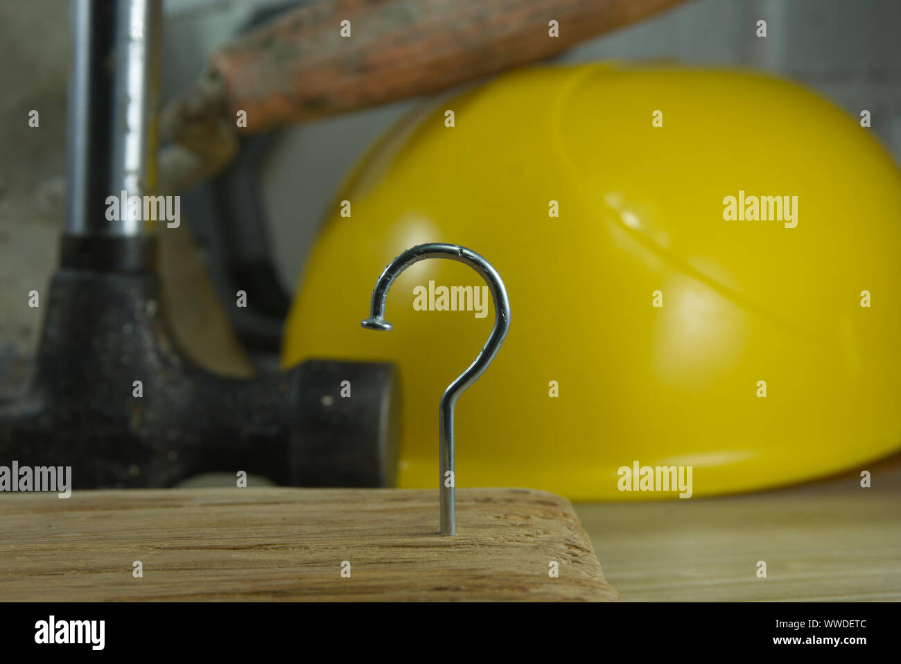 Construction nail shaped as question mark with blurred background of ...