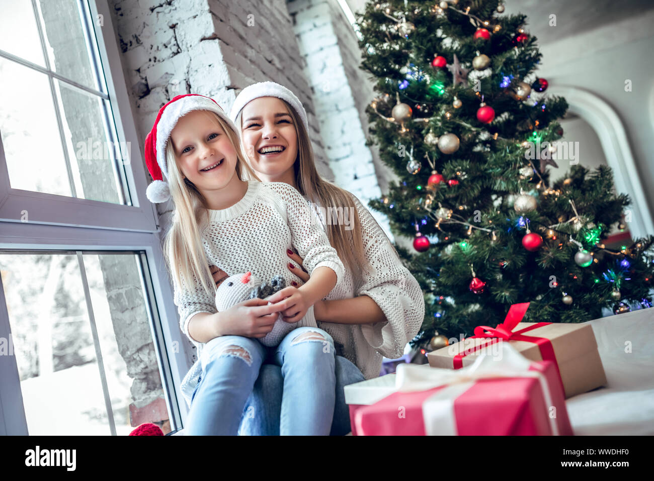 Beautiful mom santa hugging girl kid and smile joyfully. lovely ...