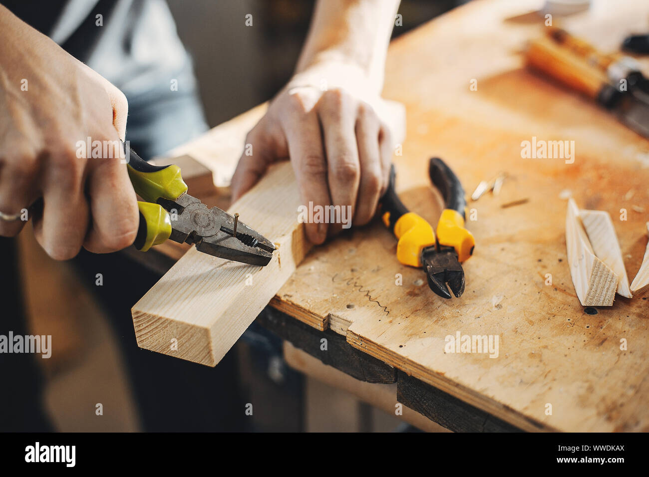 A man carves a tree. The carpenter works with pliers in a studio. An ...
