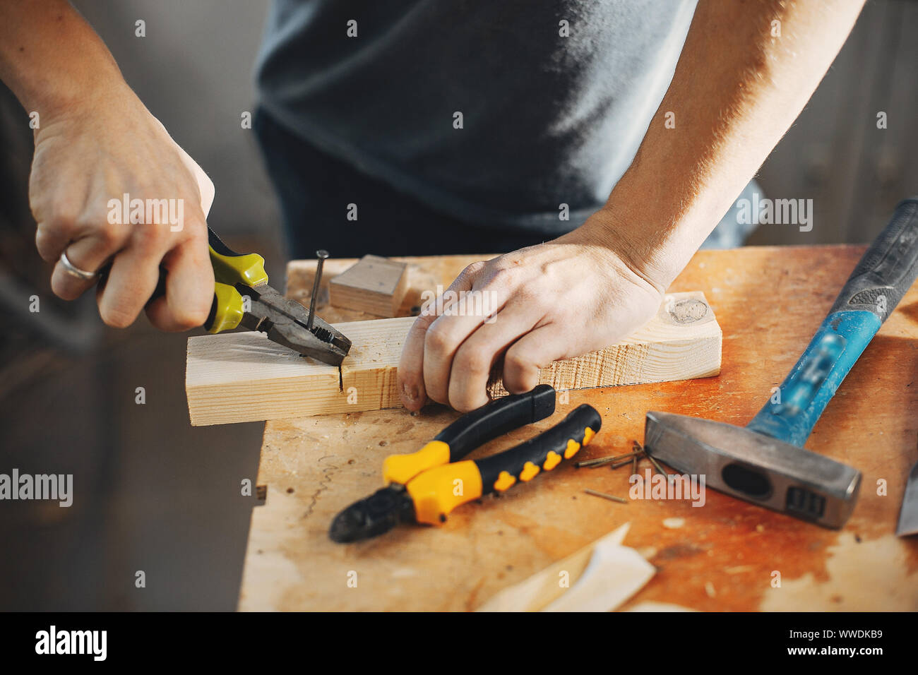 A man carves a tree. The carpenter works with pliers in a studio. An ...