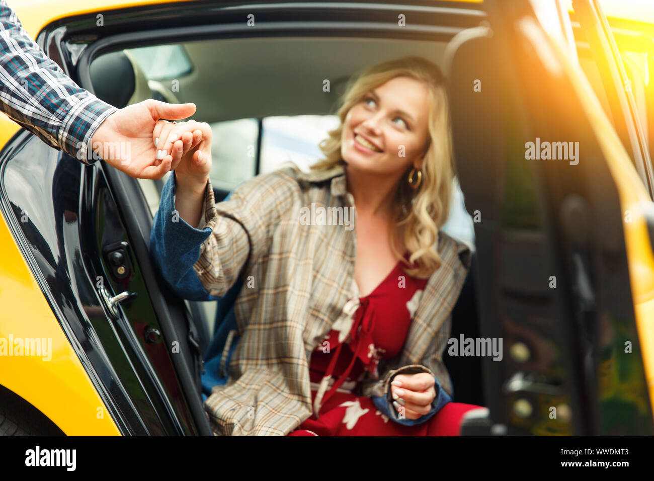 Photo of man giving hand to blonde woman sitting in back seat of taxi ...