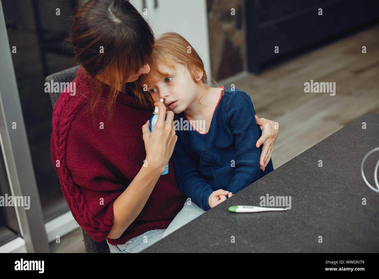 Little girl fell ill. A young mother drops nose drops for the baby ...
