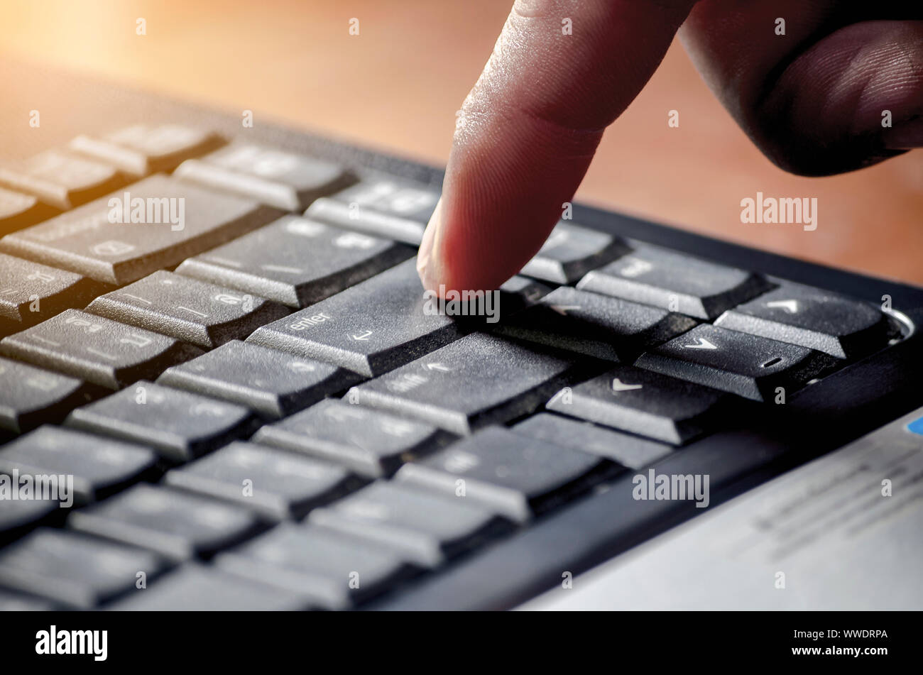 Businessman presses a Enter button on the black keyboard with sunlight ...