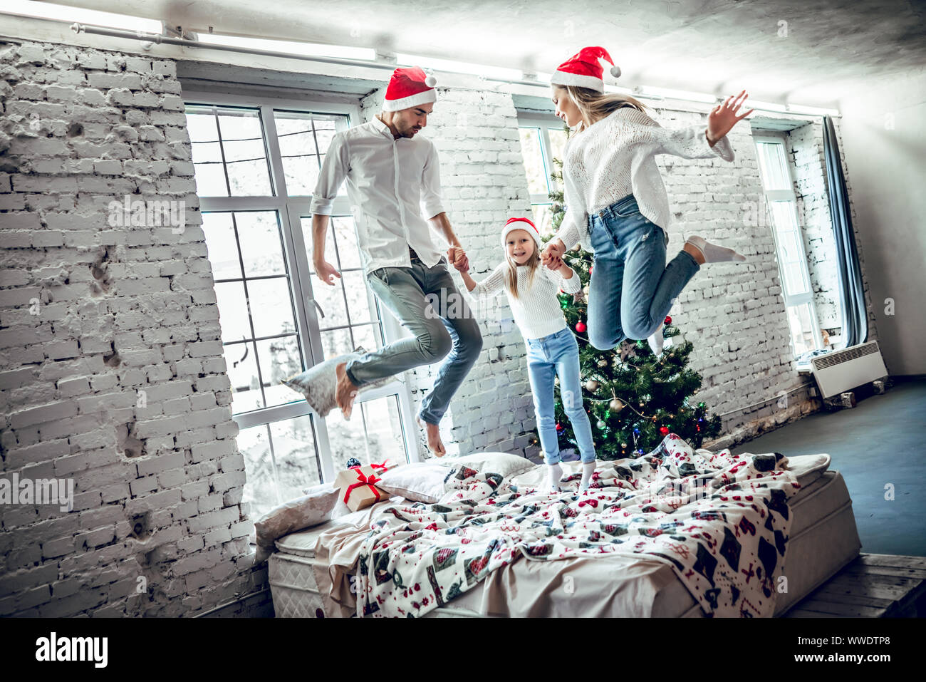 The beautiful family in Santa hat jumping on the bed. New Year and xmas ...