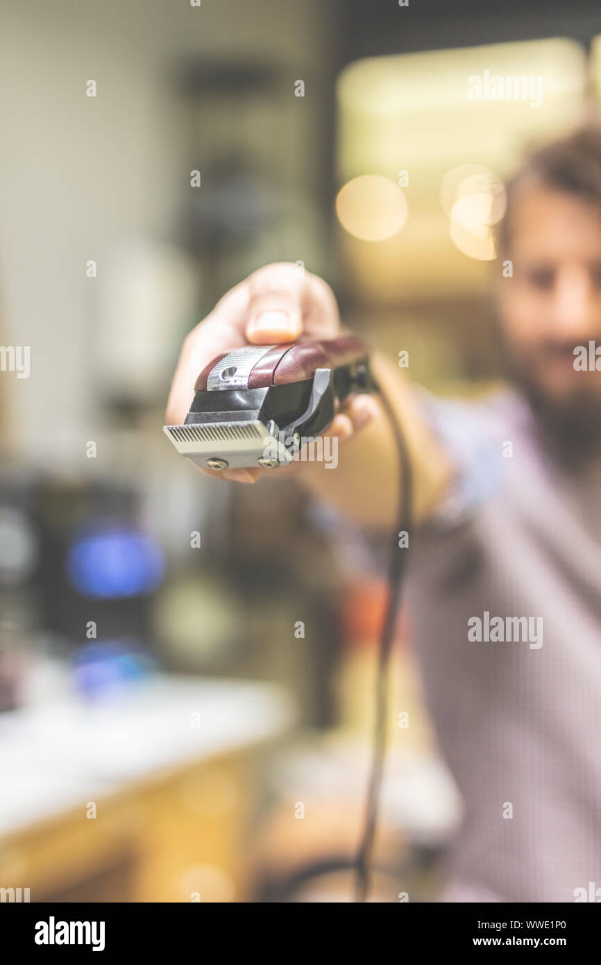 Modern barber holding hair clipper at barbershop Stock Photo - Alamy