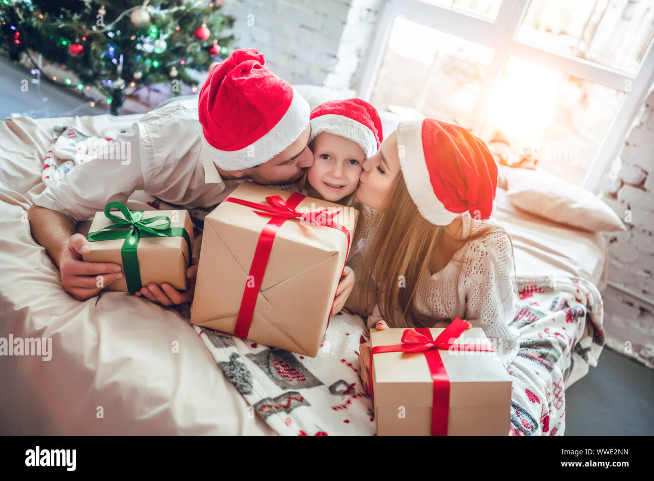 Beautiful family in Christmas interior.Happy parents kissing daughter ... Beautiful family in Christmas interior.Happy parents kissing daughter ...
