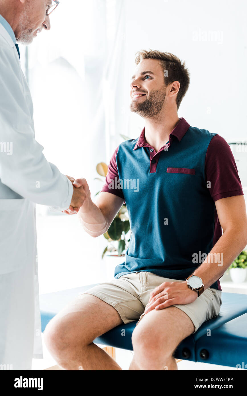 happy patient shaking hands with bearded doctor in white coat Stock ...